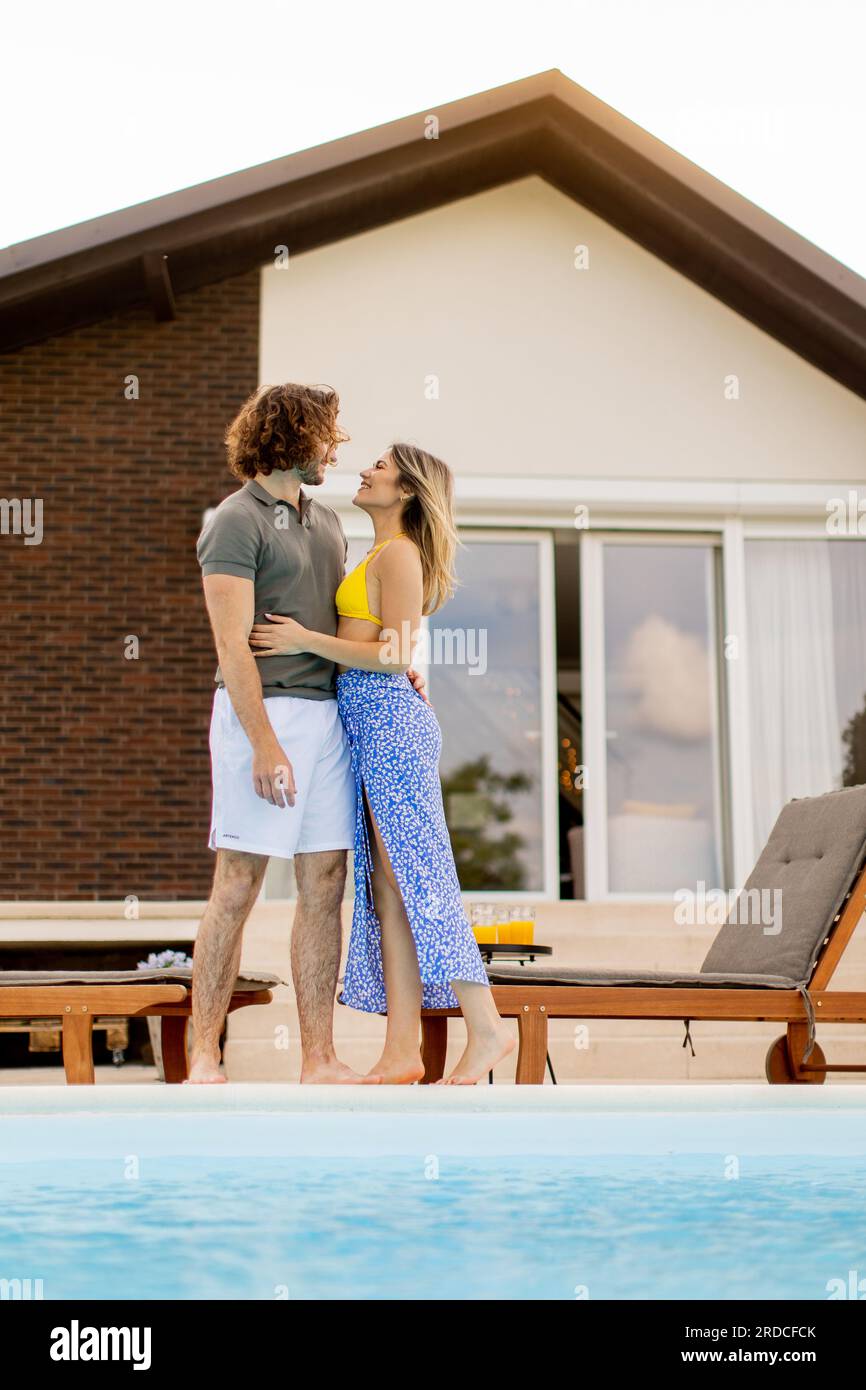 Handsome young couple relaxing by the swimming pool in the house ...
