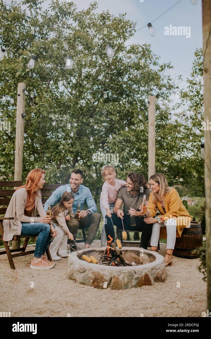 Group of friends having good time and baking corns in the house ...