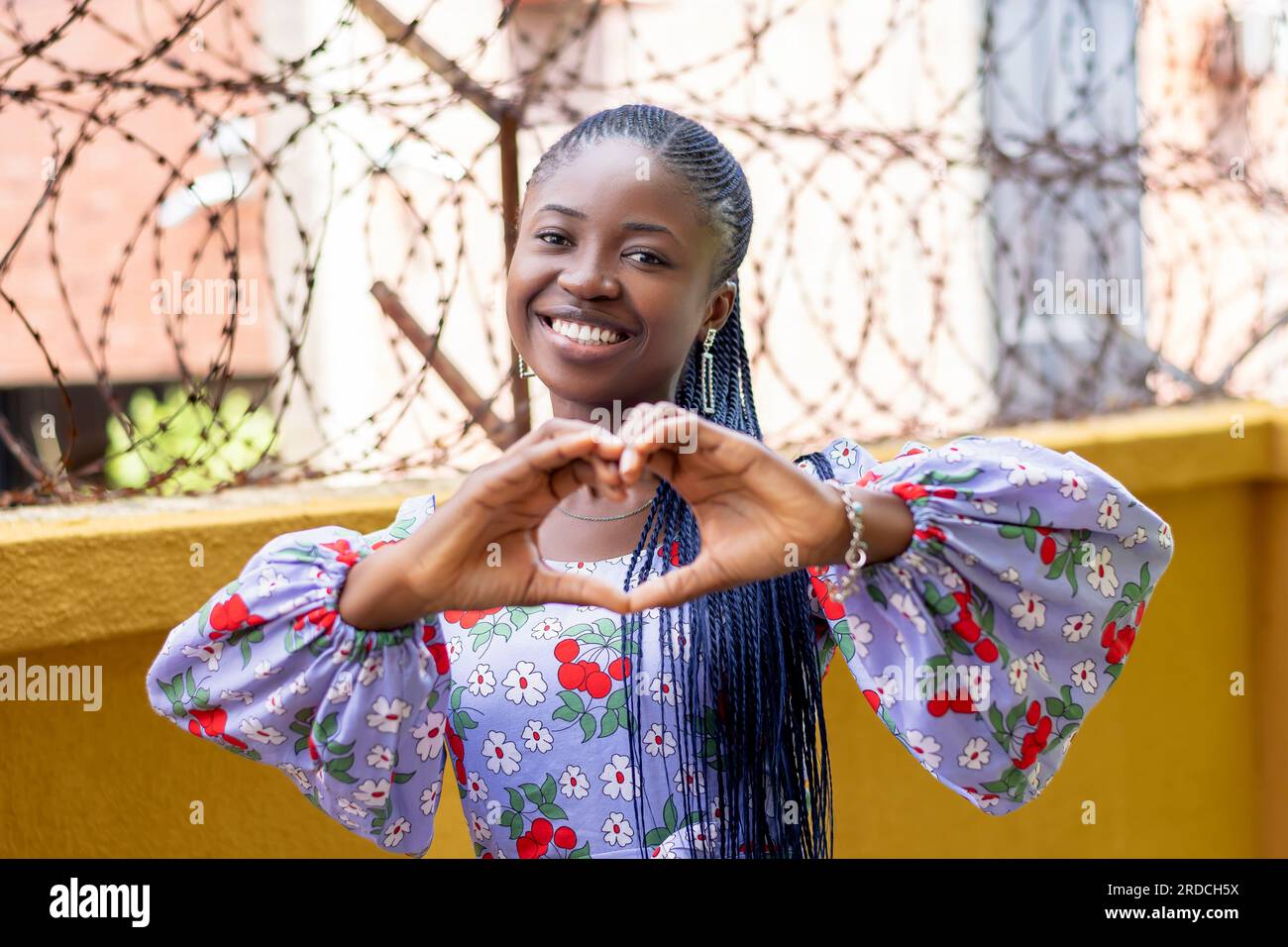Photo of a joyful African woman creating a heart shape with her hands ...