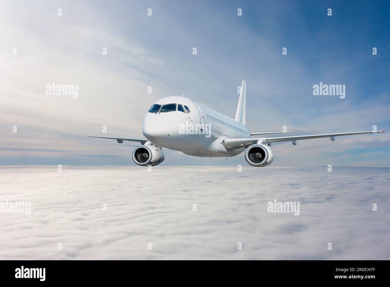 Modern white passenger jetliner flying in the sky above the clouds ...