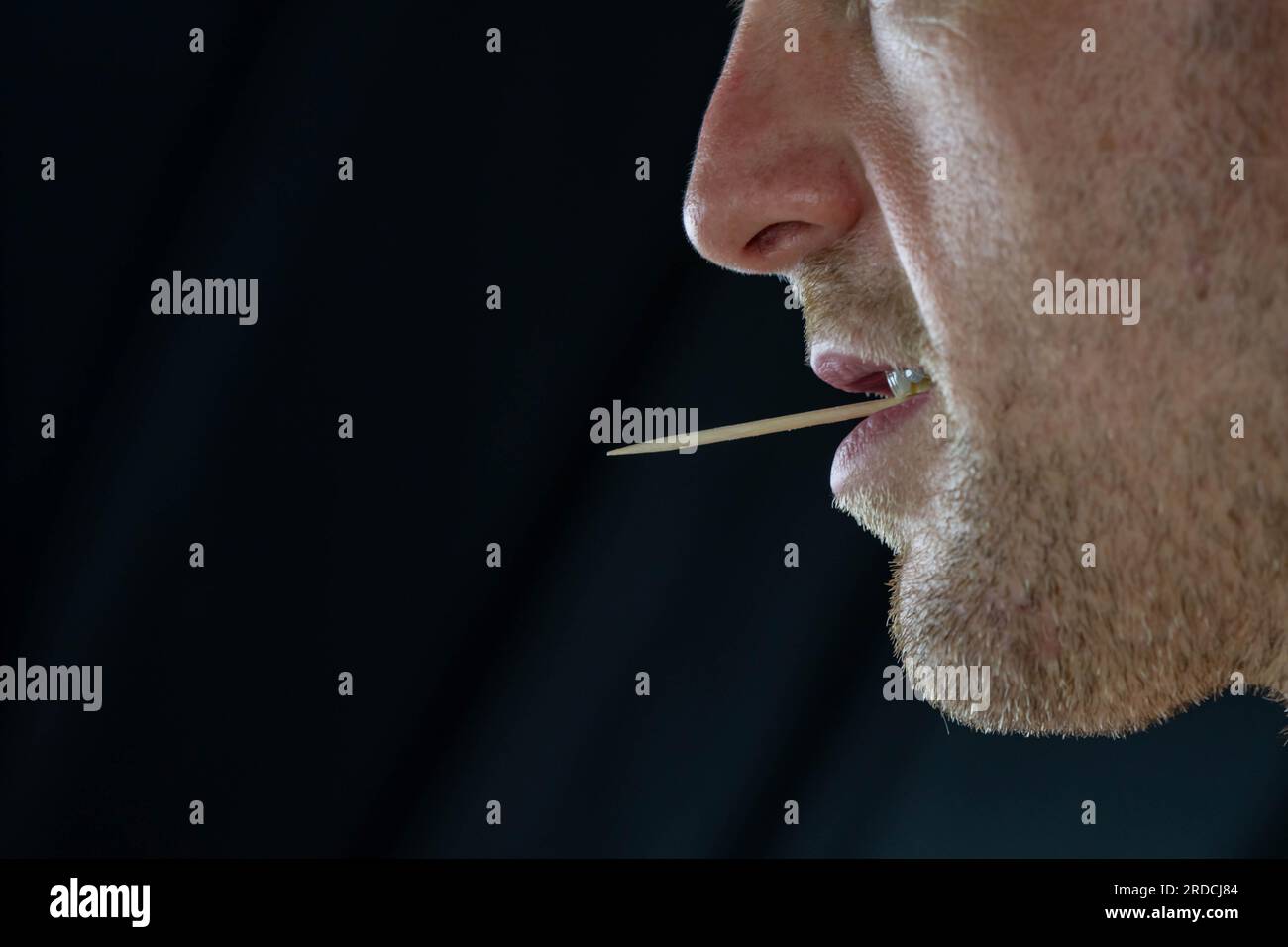 close up abstract shot of toothpick in a man mouth black background ...