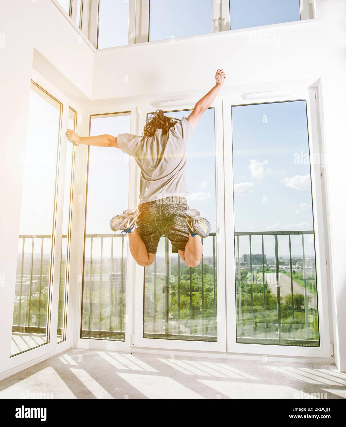 a man with long hair jumping for joy in a new apartment located very ...