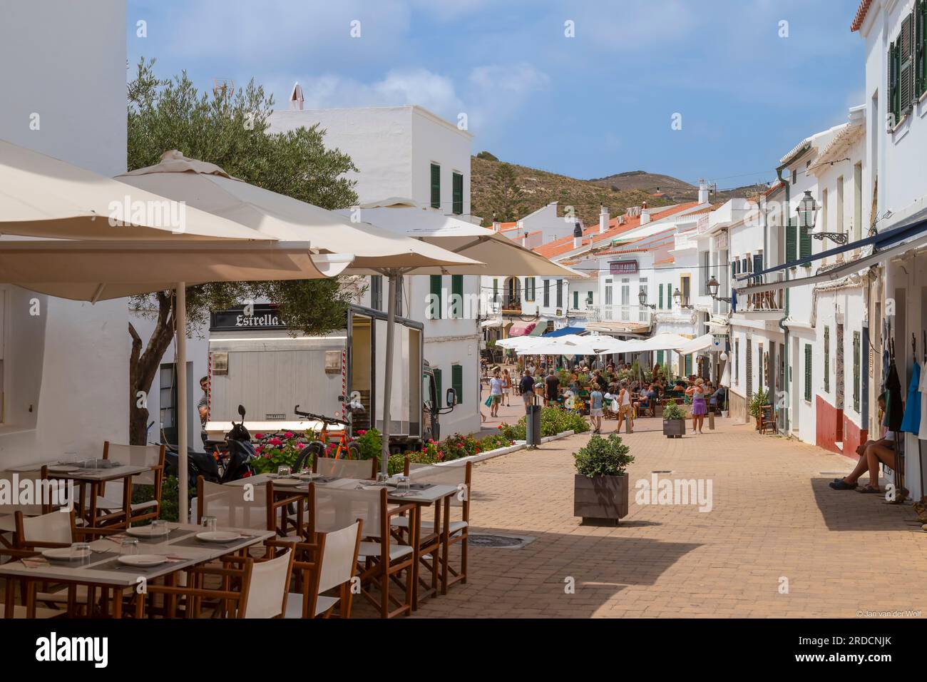 Tourists walk through a narrow cozy street with restaurants and shops ...