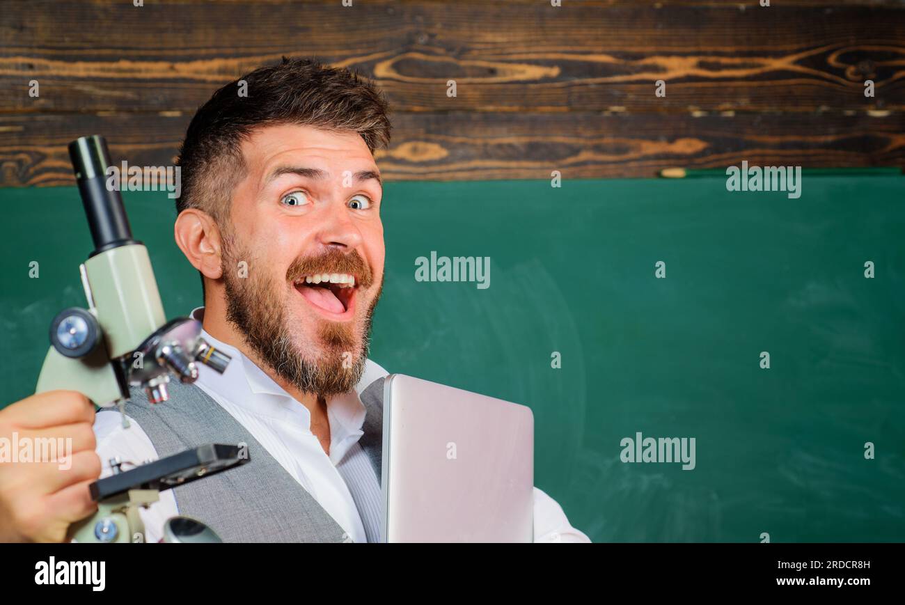 Happy male teacher with laptop and microscope. Student with notebook ...