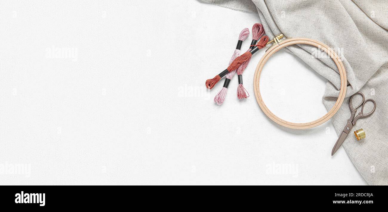 Wooden embroidery hoops with scissors, thimble and threads on light ...