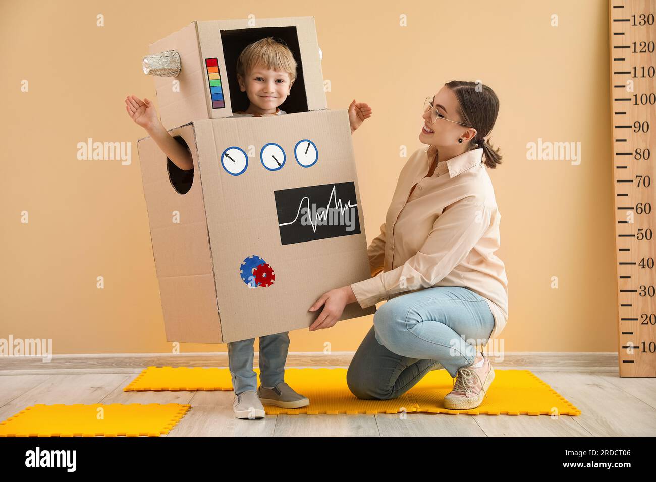 Little boy in cardboard robot costume with nanny at home Stock Photo ...