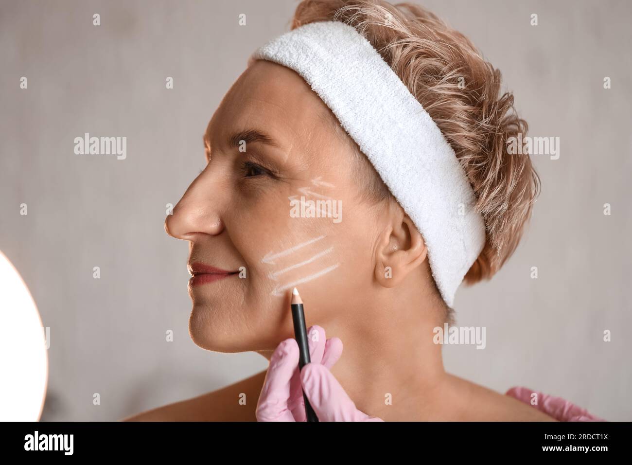 Beautician marking mature woman's face for filler injection in salon ...
