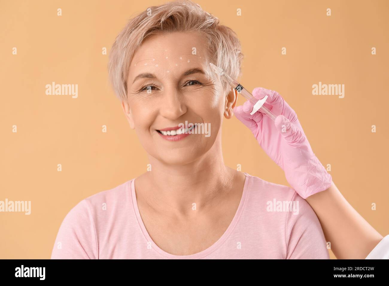 Mature woman receiving filler injection on beige background, closeup ...