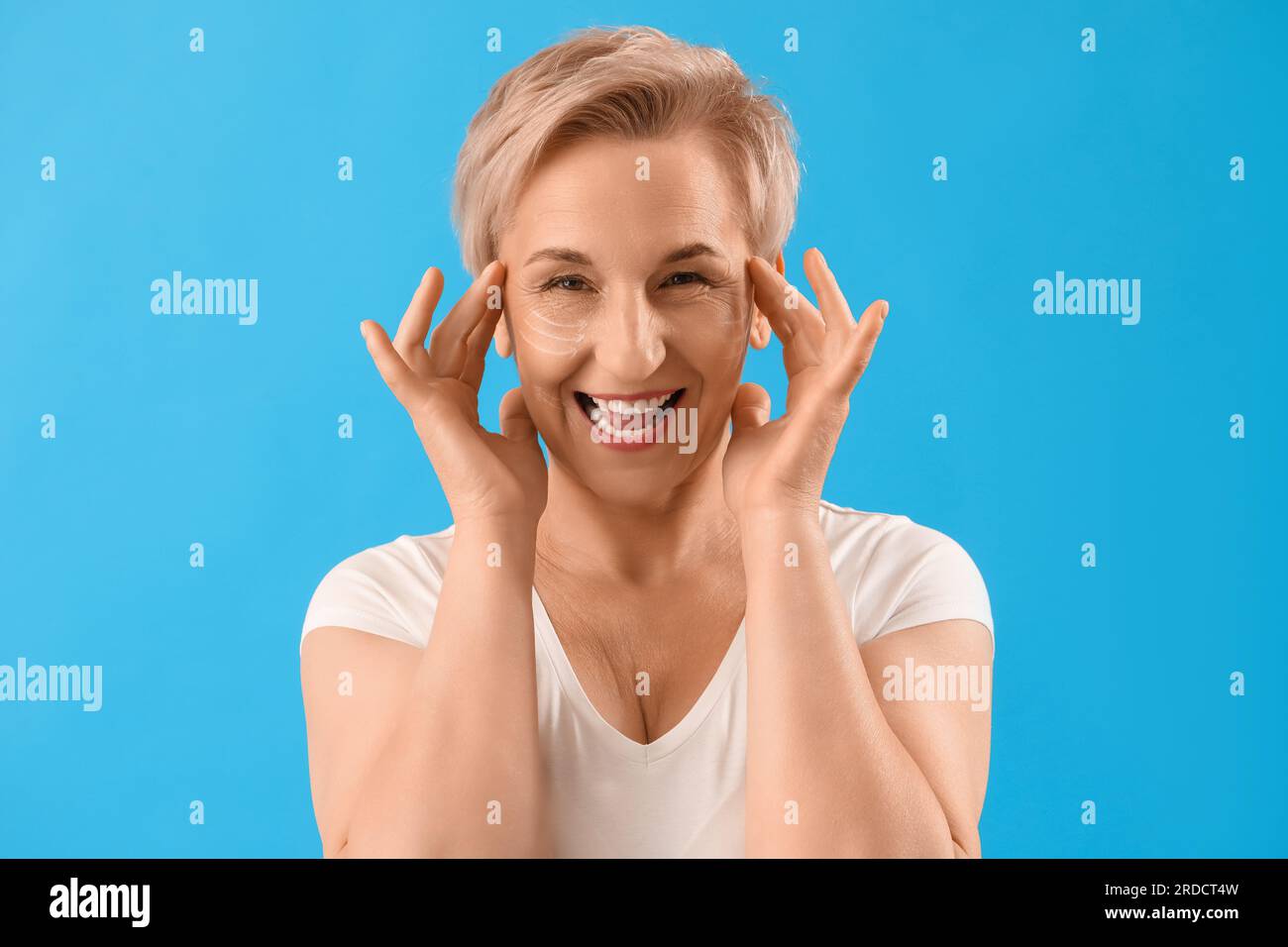 Mature woman with marked face for filler injection on blue background ...