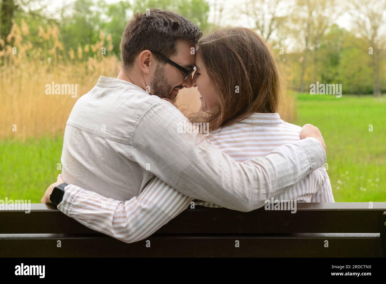 Beautiful loving couple sitting on bench and hugging in park Stock ...