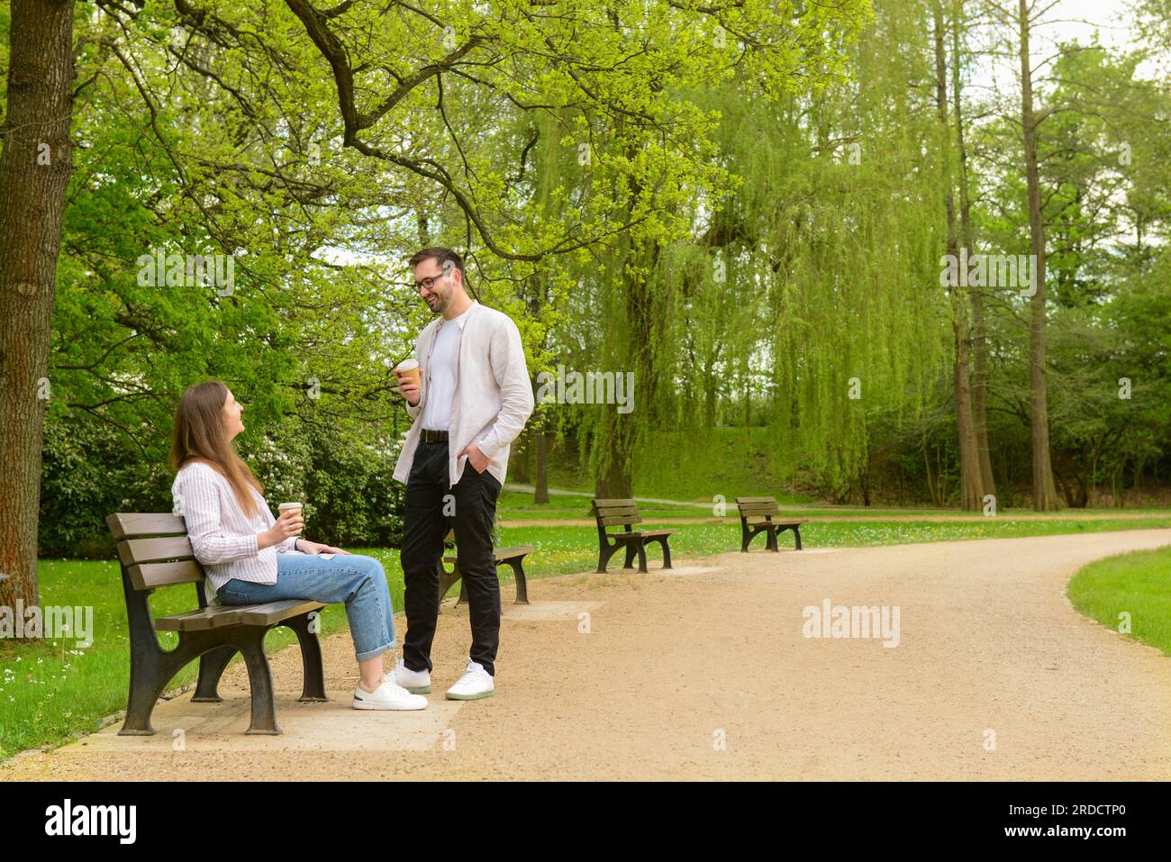 Couple drinking coffee on park bench hi-res stock photography and ...