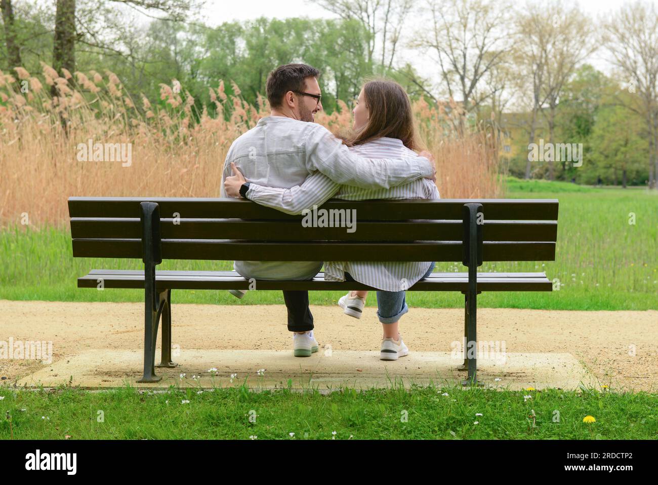 Beautiful loving couple sitting on bench and hugging in park Stock ...