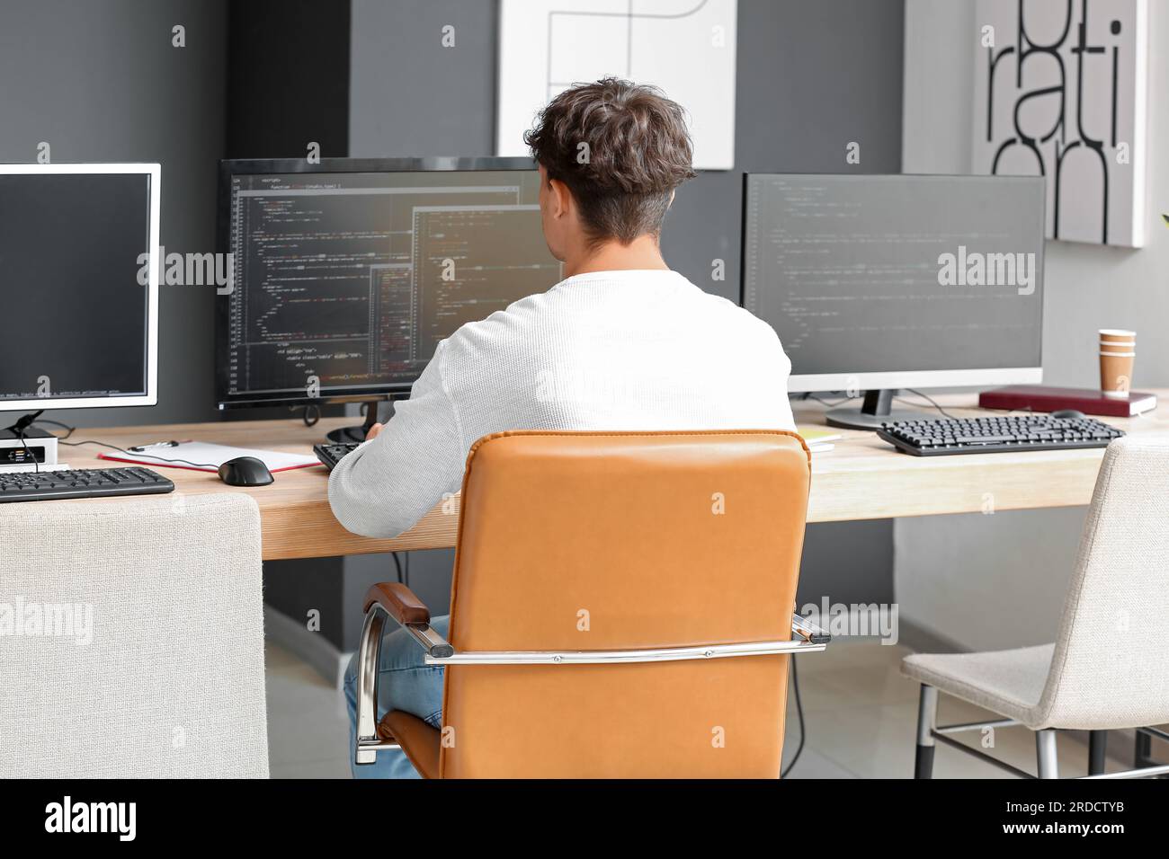 Male programmer working with computer at table in office, back view ...