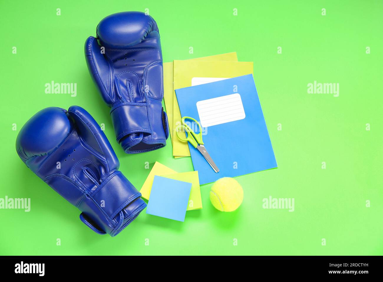 Boxing gloves with tennis ball and different stationery on green ...
