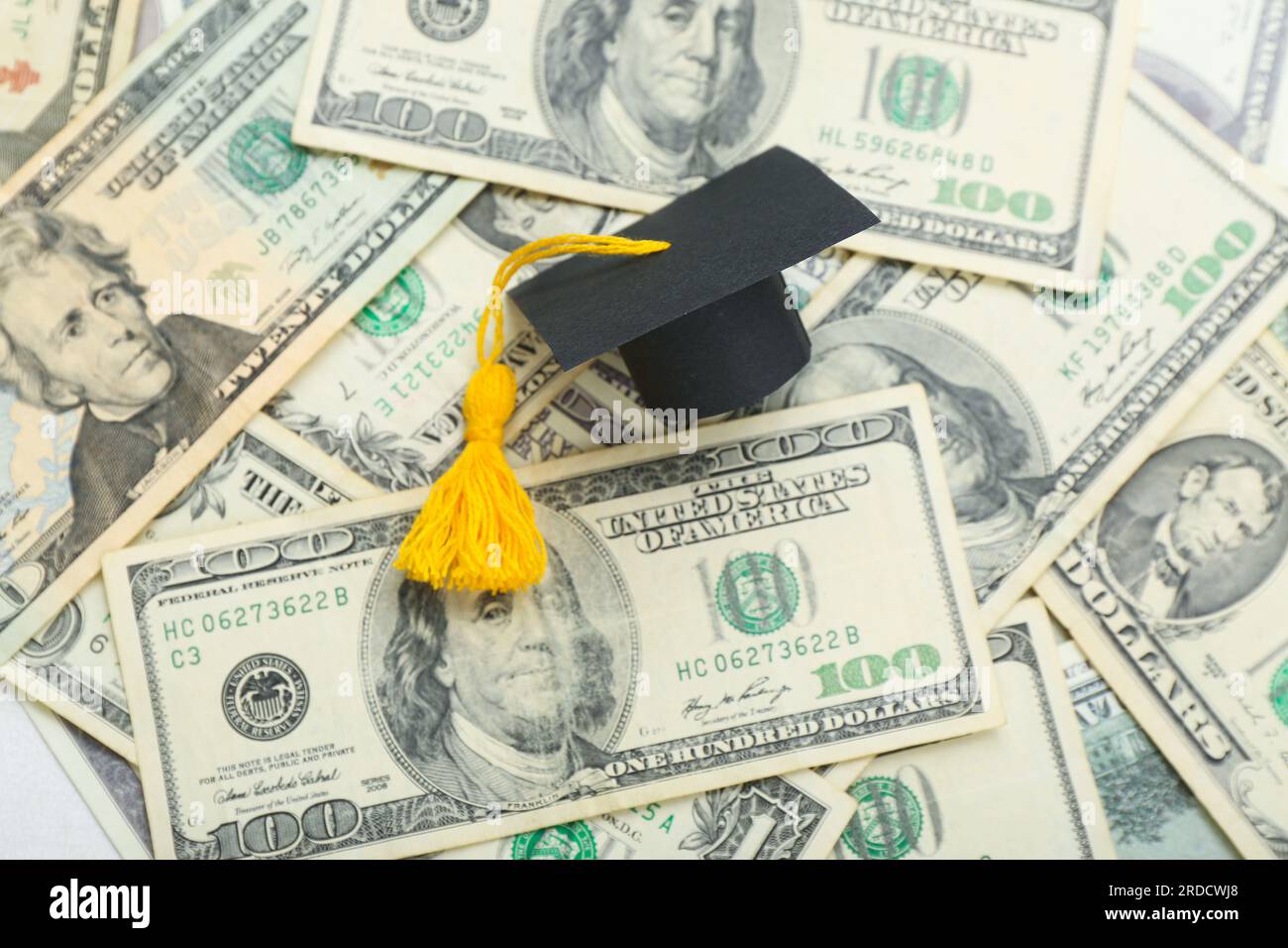 Graduation hat on pile of dollar banknotes. Student loan concept Stock ...
