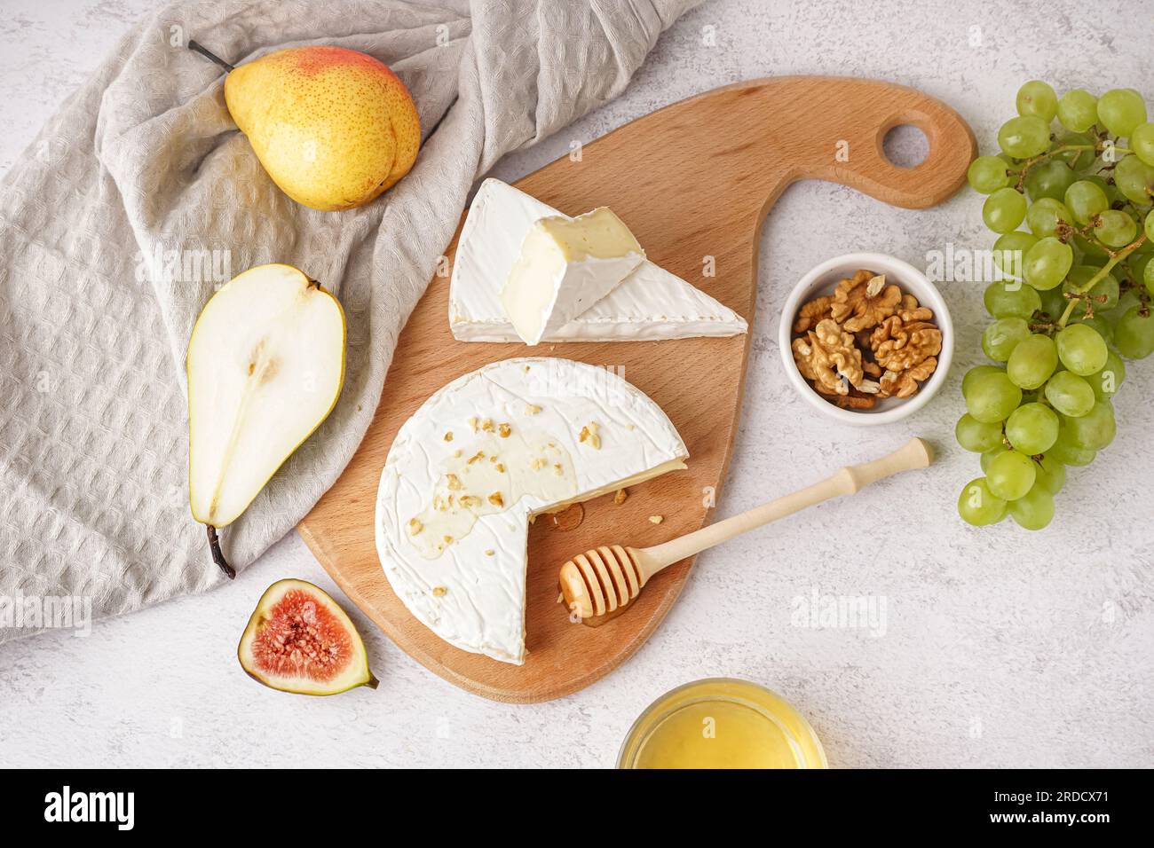 Wooden board with pieces of tasty Camembert cheese on light background ...