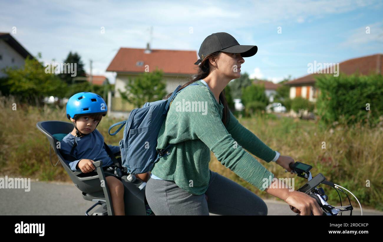 Cyclist mother rides bike outside in green road with child Stock Photo ...