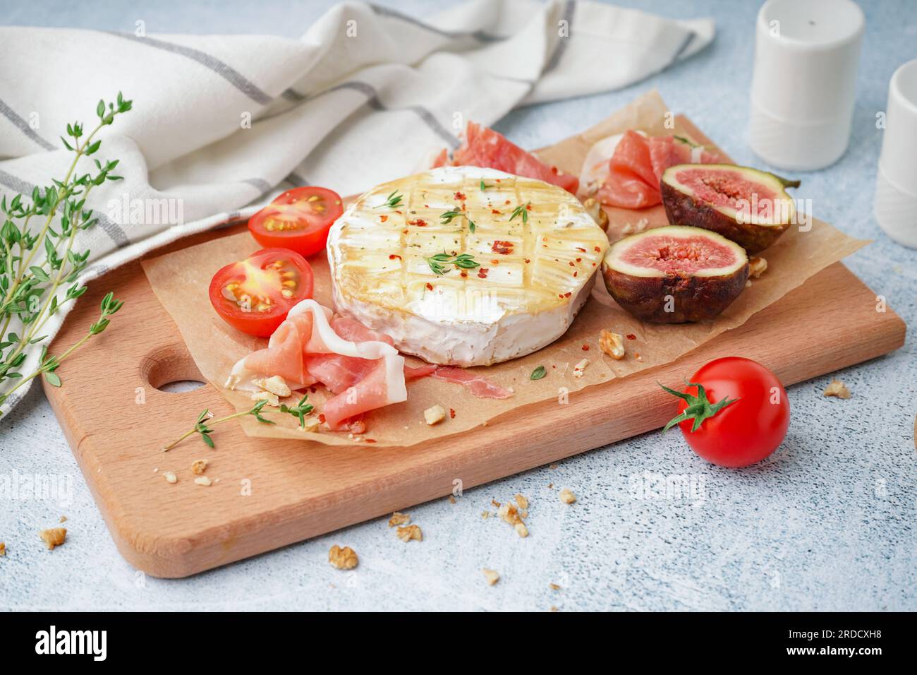 Wooden board with tasty baked Camembert cheese on light background ...
