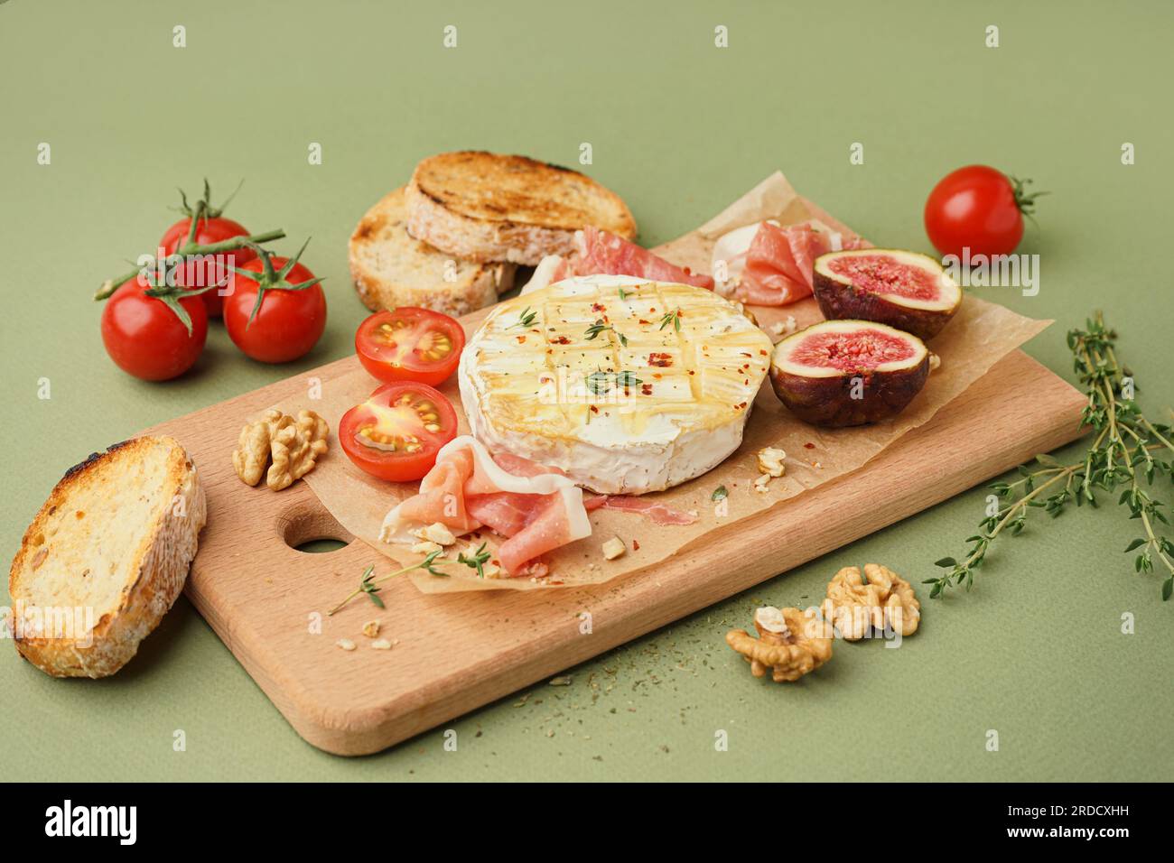 Wooden board with tasty baked Camembert cheese on green background ...