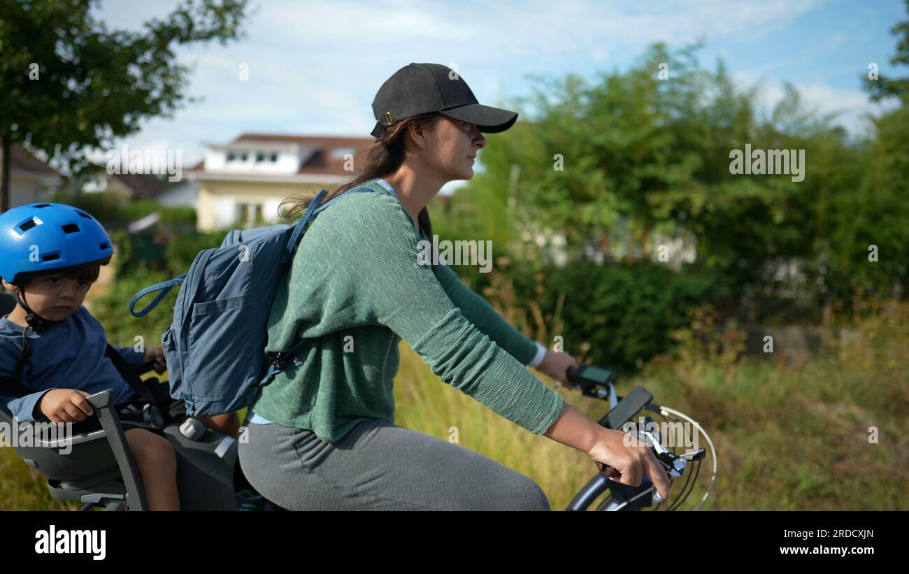 Cyclist mother rides bike outside in green road with child Stock Photo ...