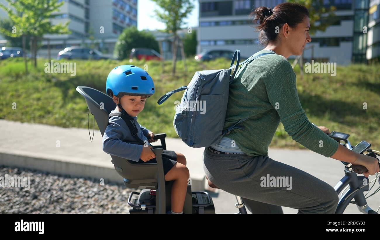 Mother riding bicycle with little boy sitting on back seat Stock Photo ...