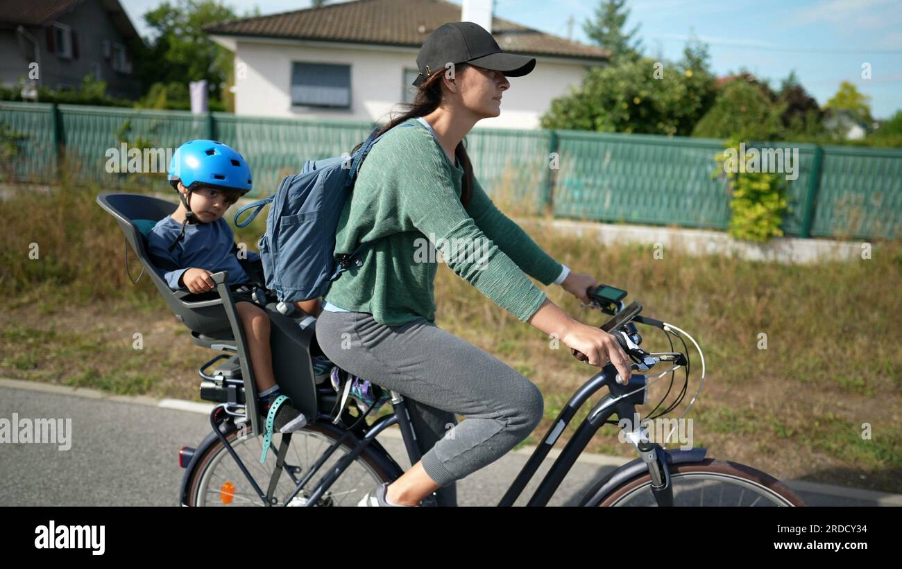 Mother riding bicycle with son in back seat mom rides bike with child ...