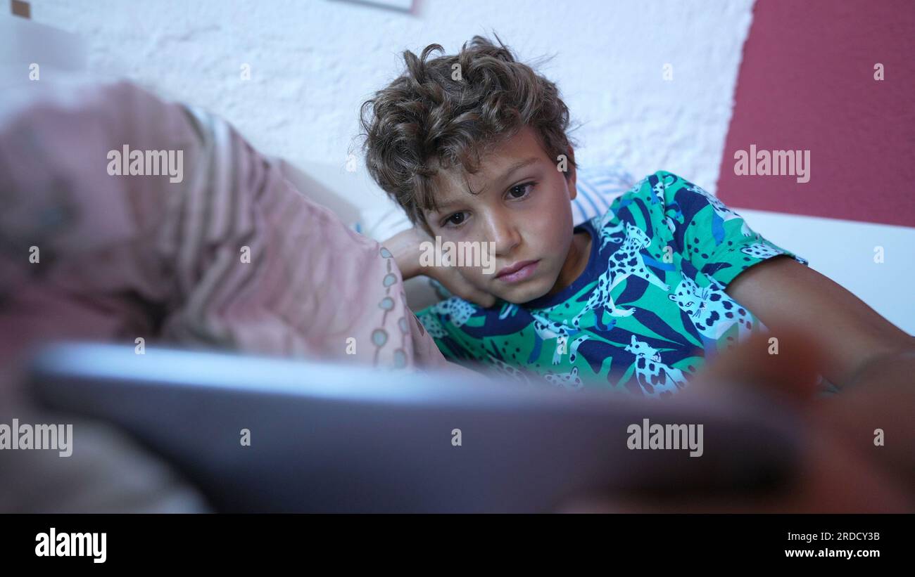 One addicted child staring at cellphone screen in the morning bed Stock ...