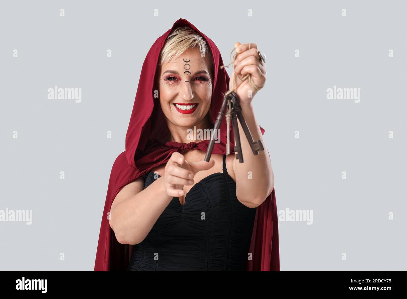 Mature witch with keys on grey background Stock Photo - Alamy