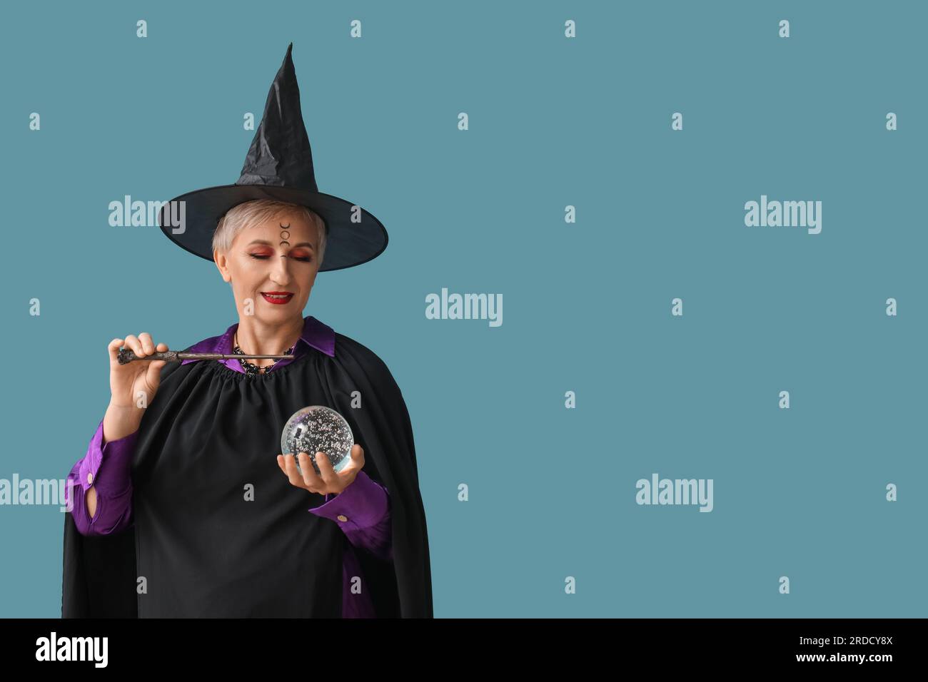 Mature witch with magic wand and crystal ball on blue background Stock ...