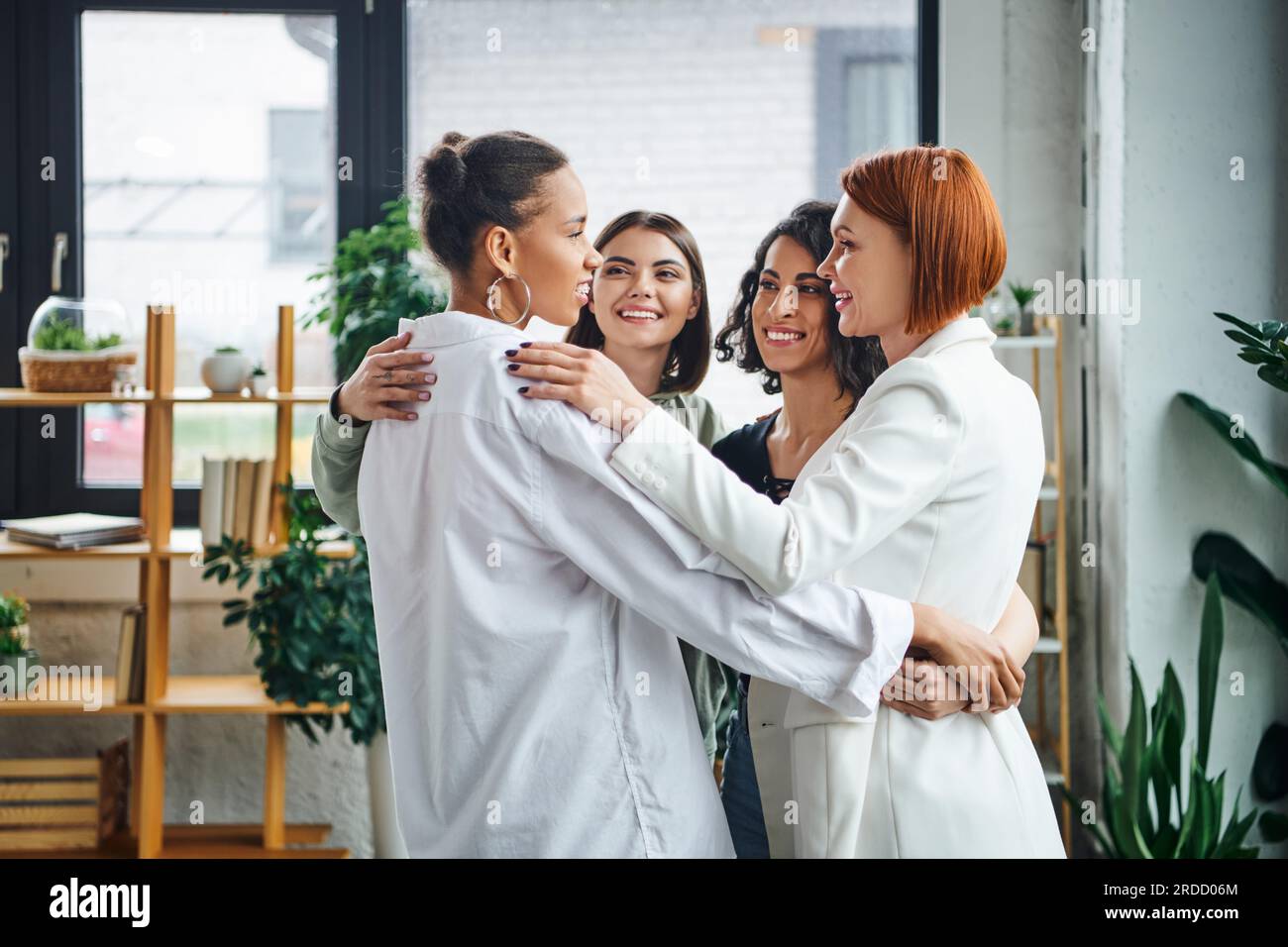 overjoyed multiethnic women and redhead motivation coach hugging and ...