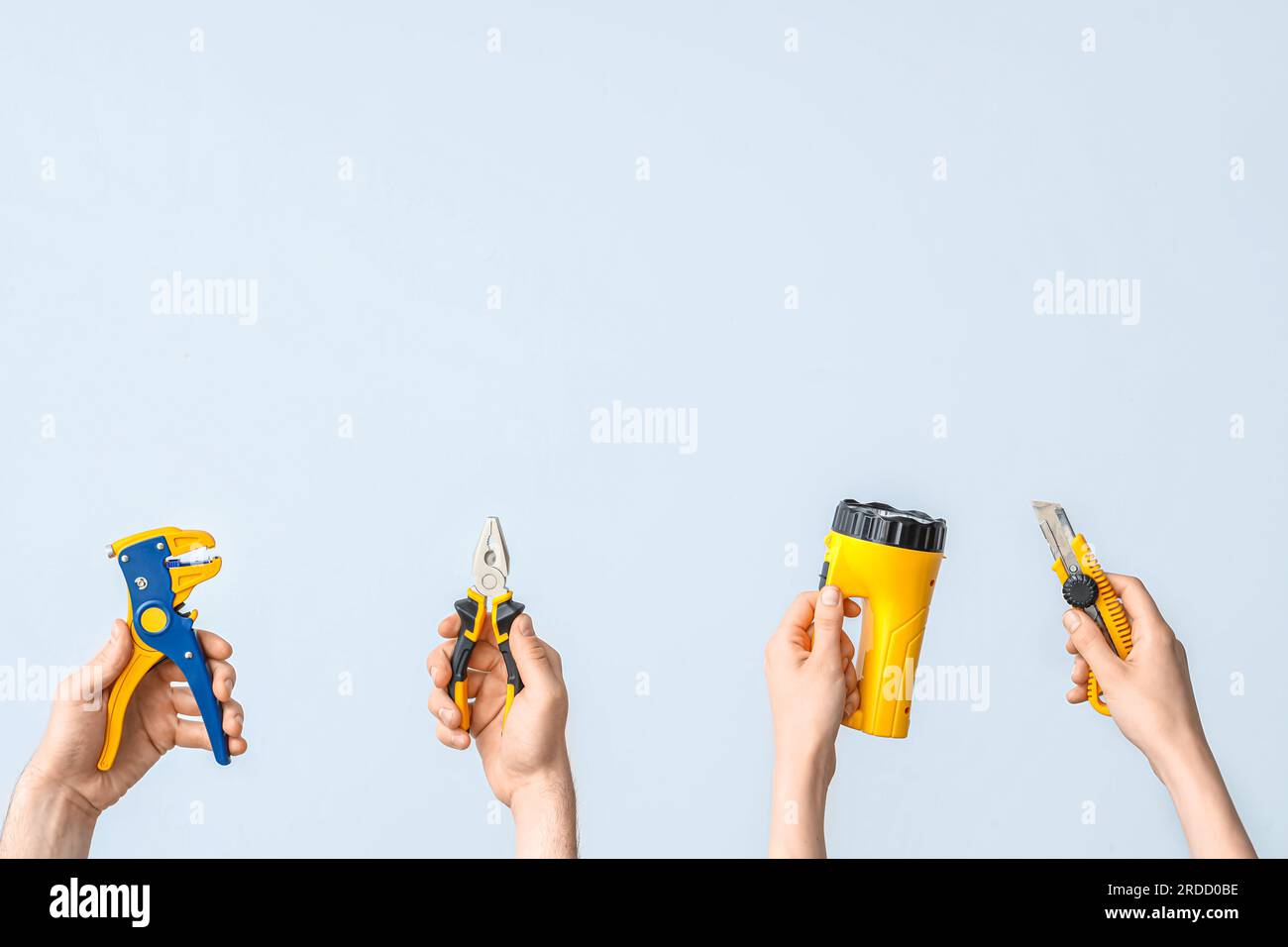 Electrician hands with tools on grey background Stock Photo - Alamy