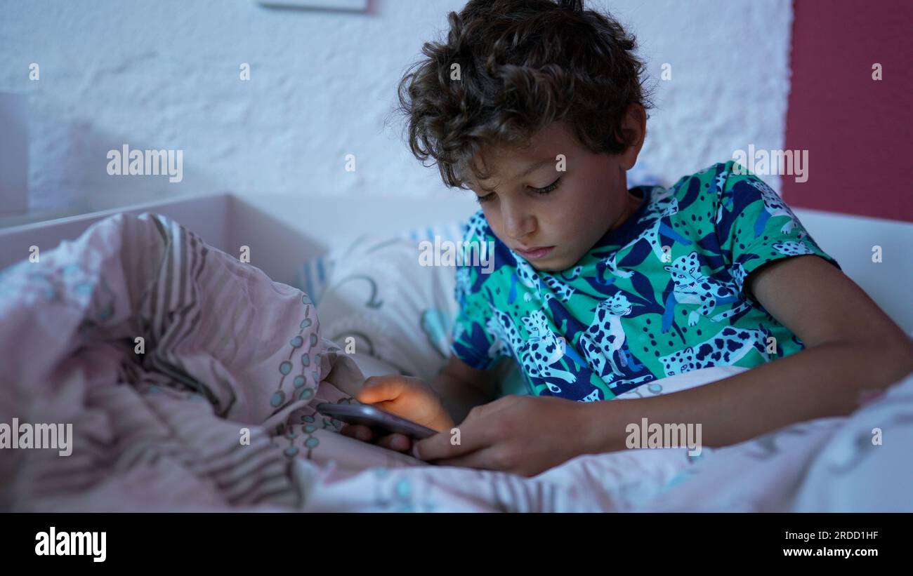 Child scrolling through phone screen in morning bed Stock Photo - Alamy