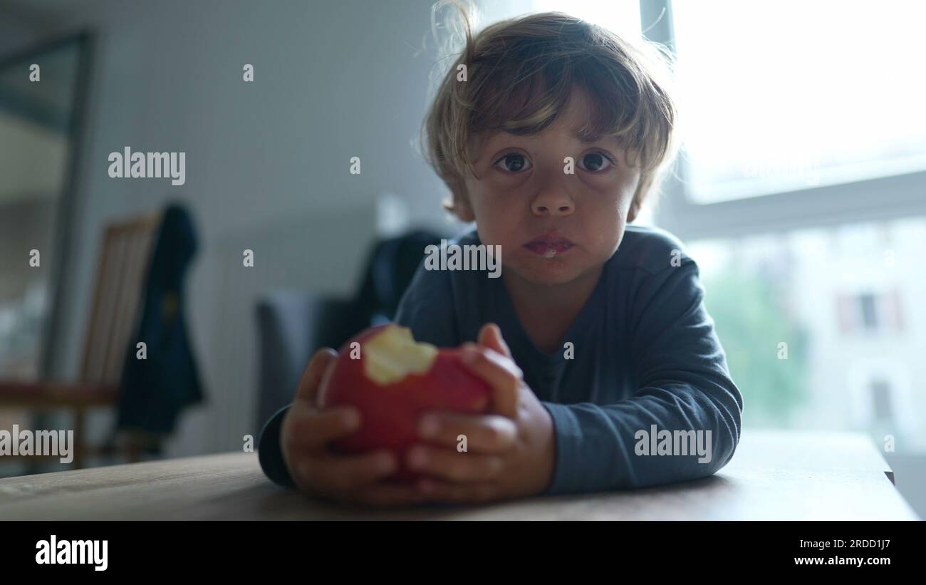 Child taking a bite of apple fruit kid eats healthy snack Stock Photo ...