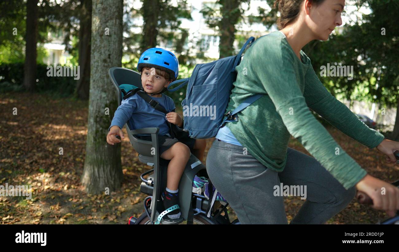 Child sitting in bicycle back seat chair with mother riding bike Stock ...
