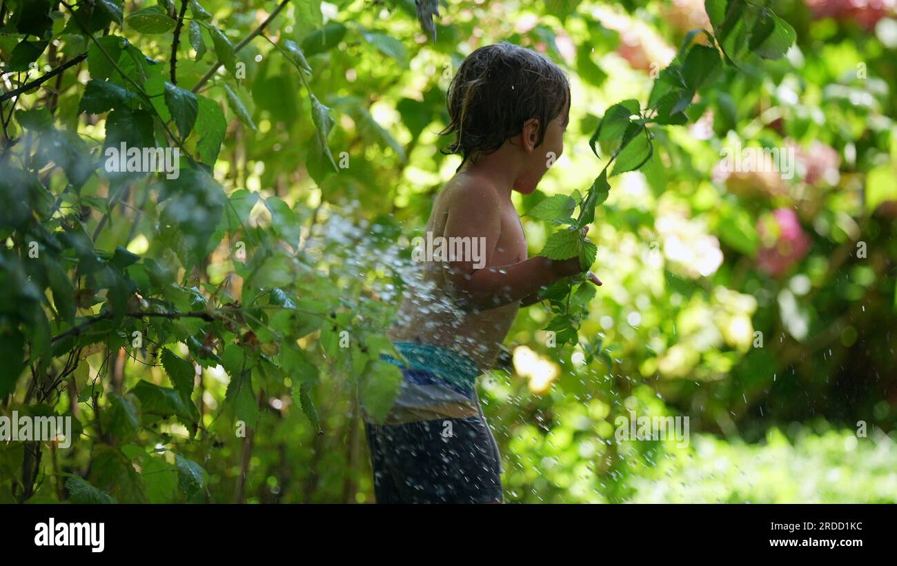 Child playing outside with water spray laughing and smiling Stock Photo ...