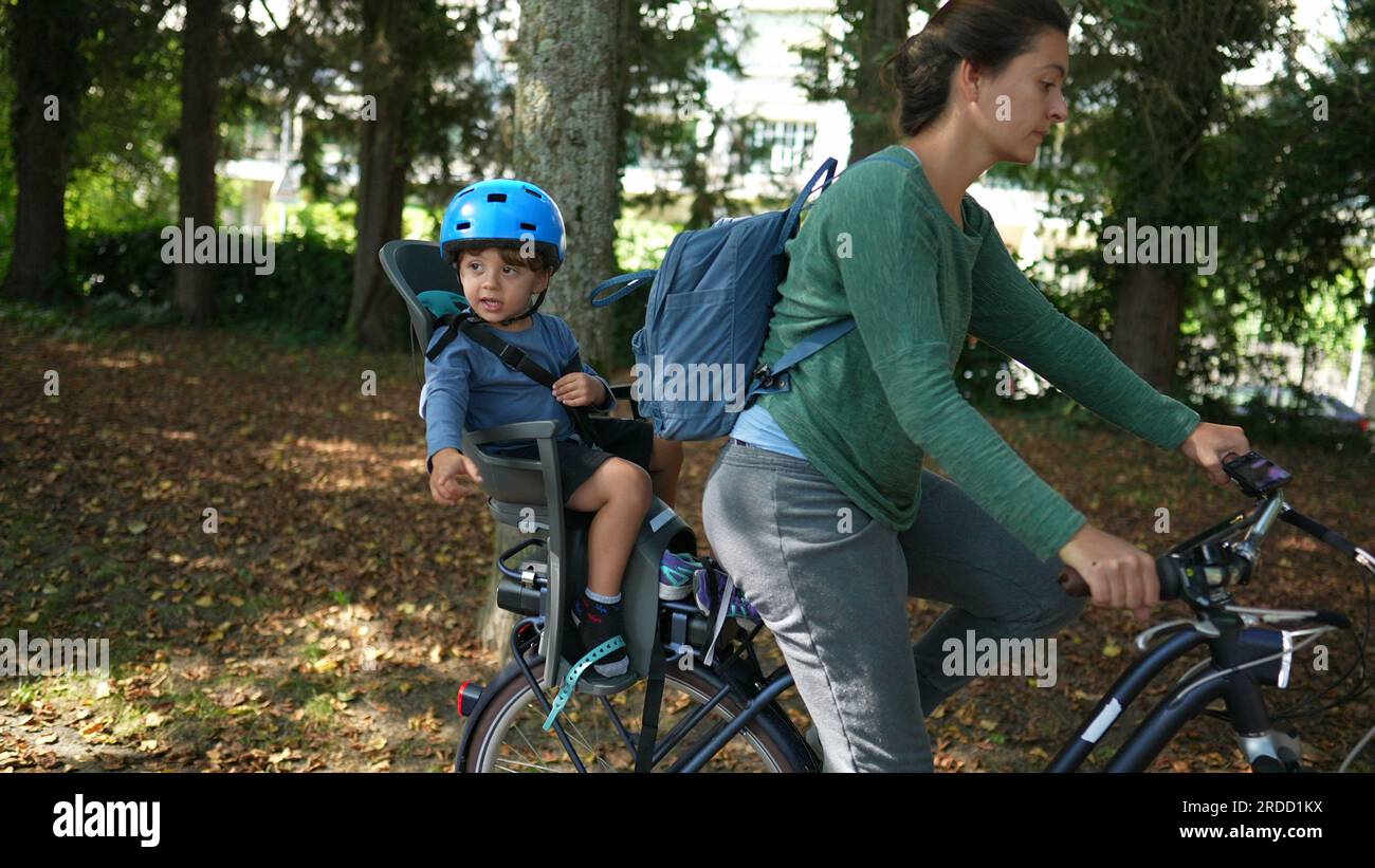 Child sitting in bicycle back seat chair with mother riding bike Stock ...