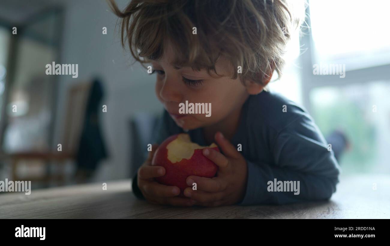 Child taking a bite of apple fruit kid eats healthy snack Stock Photo ...