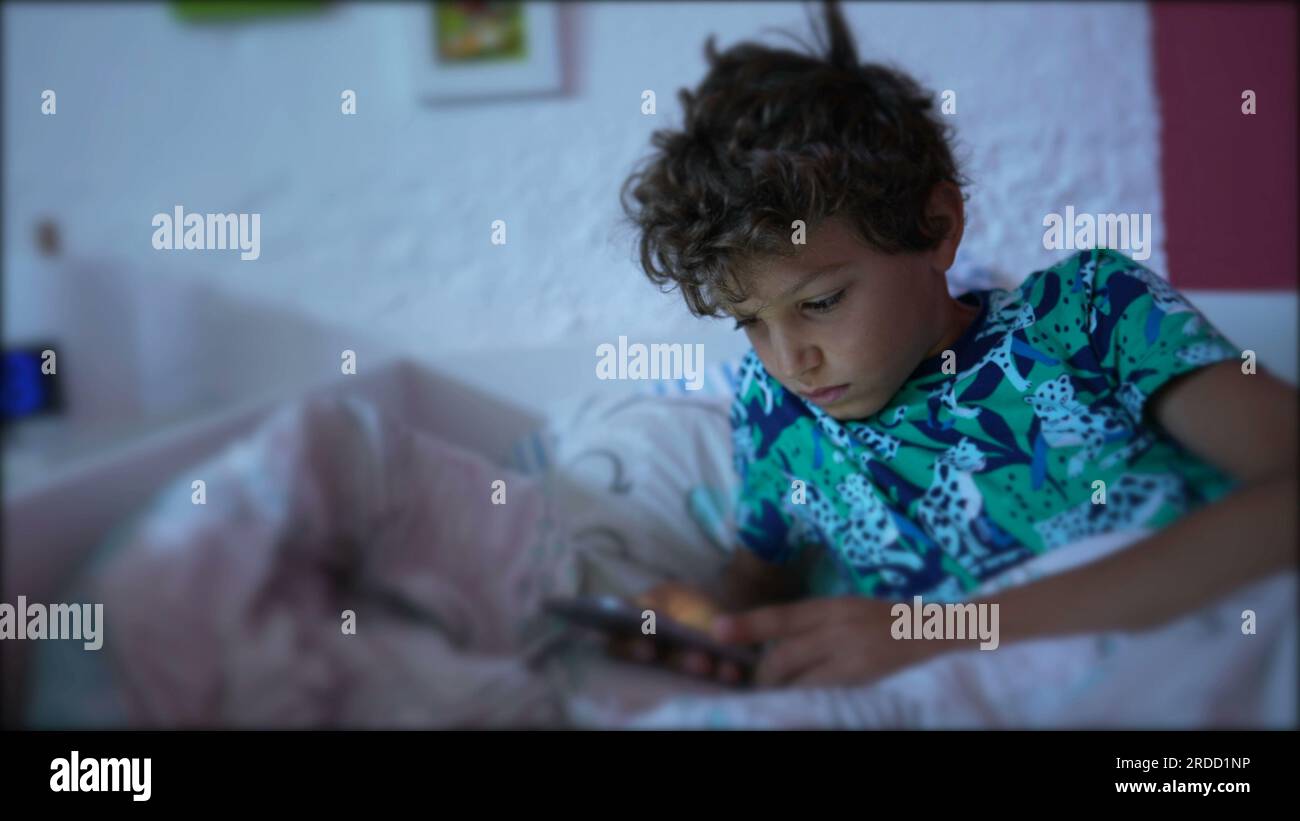 Child using smartphone in bed kid staring at phone screen Stock Photo ...