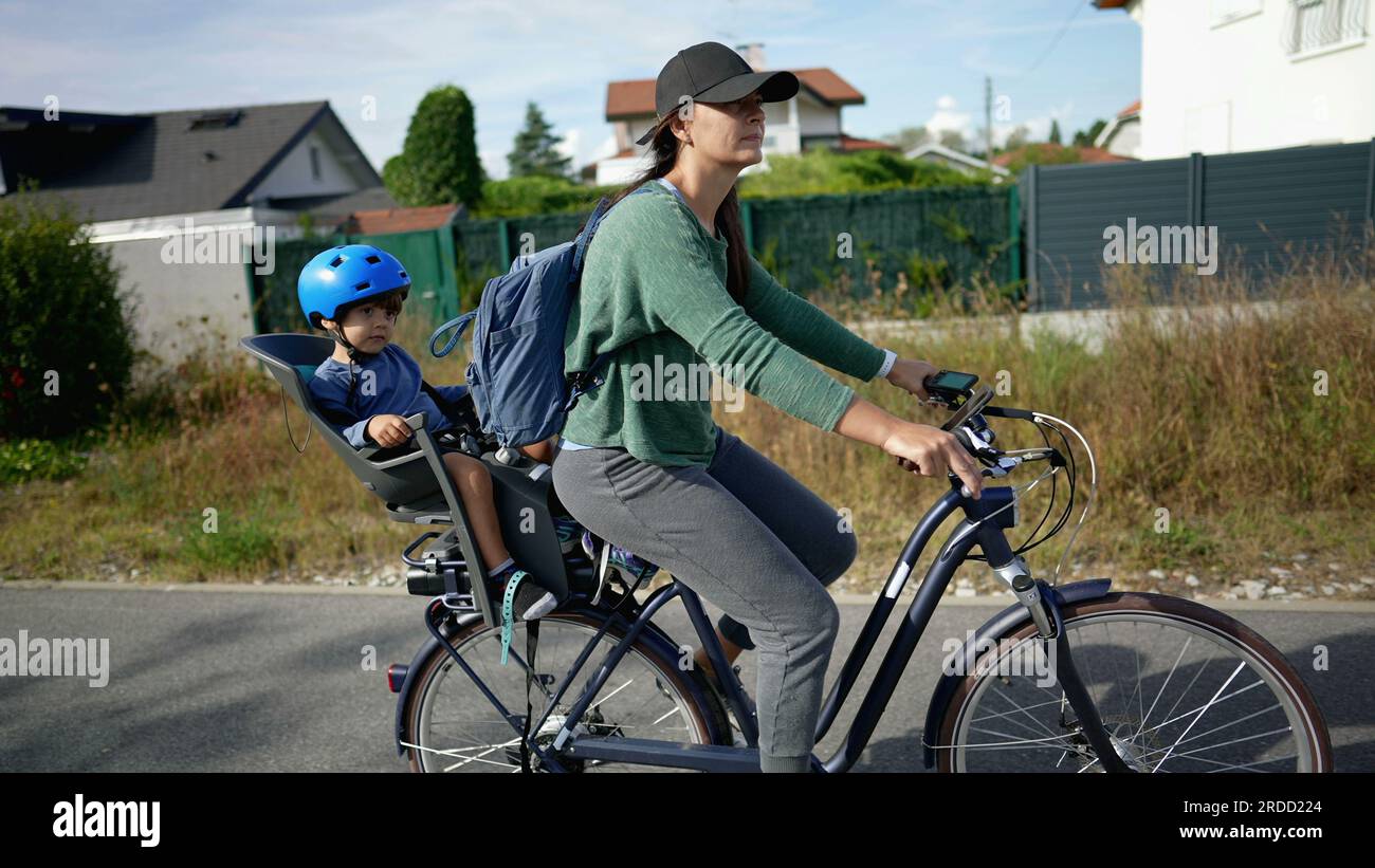 Cyclist mother rides bike outside in green road with child Stock Photo ...