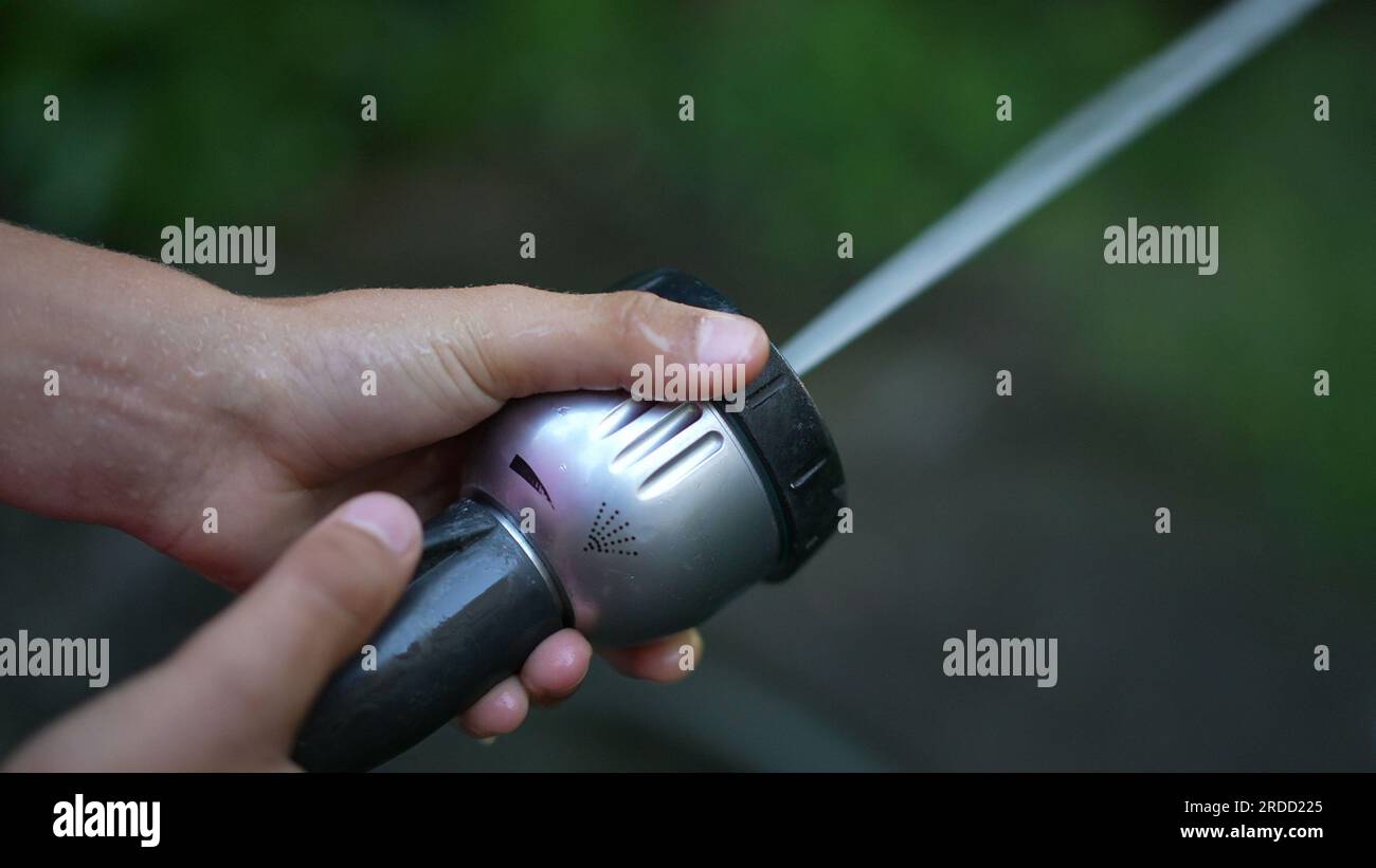 Closeup of hand holding fire hose pressing water watering garden Stock ...