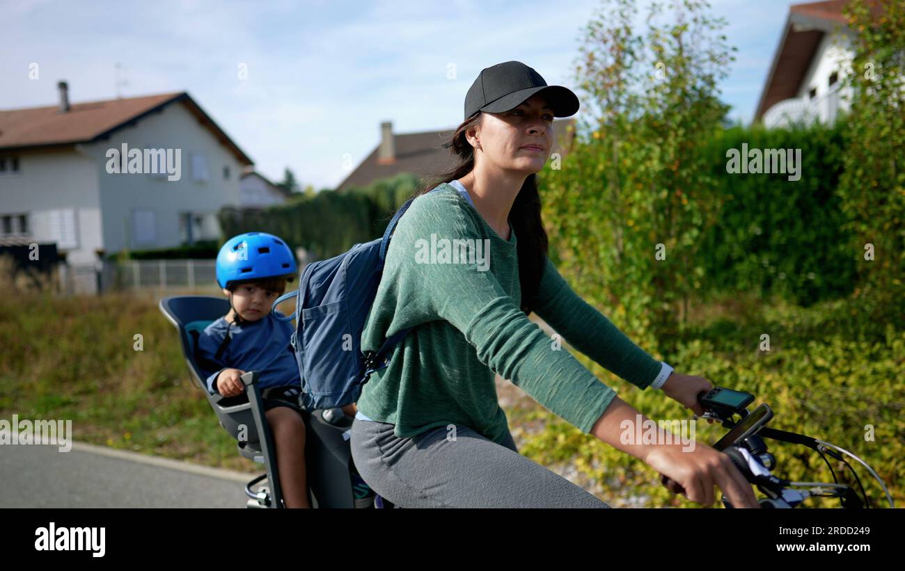 Cyclist mother rides bike outside in green road with child Stock Photo ...