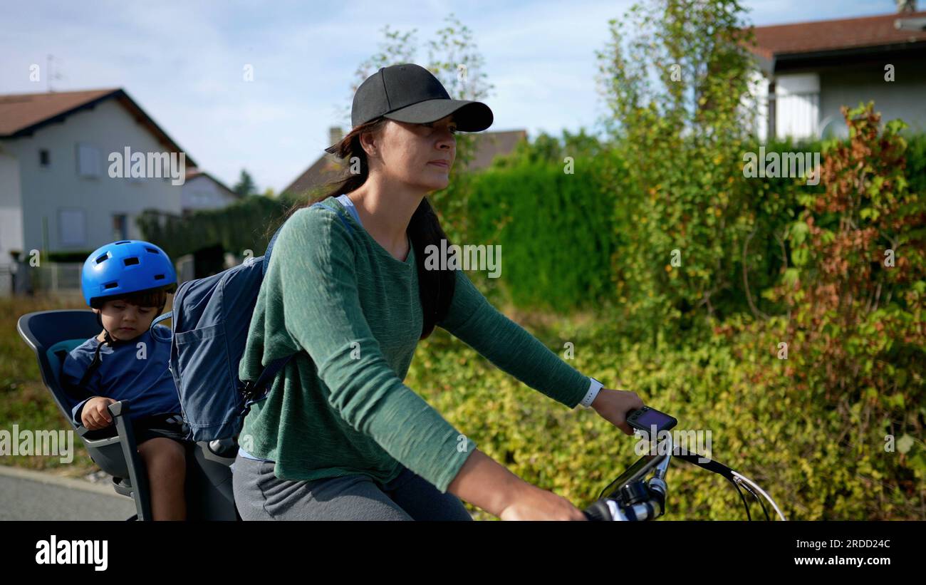 Cyclist mother rides bike outside in green road with child Stock Photo ...