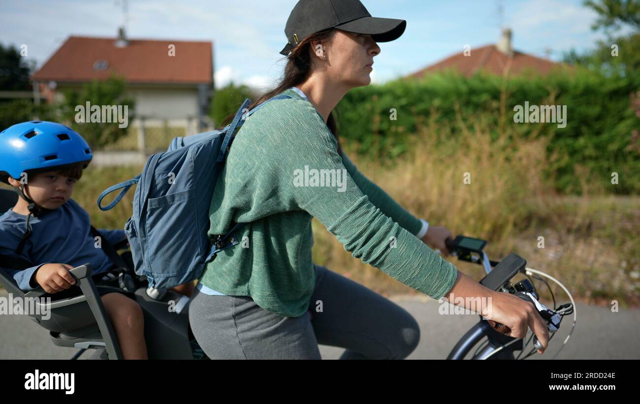 Cyclist mother rides bike outside in green road with child Stock Photo ...