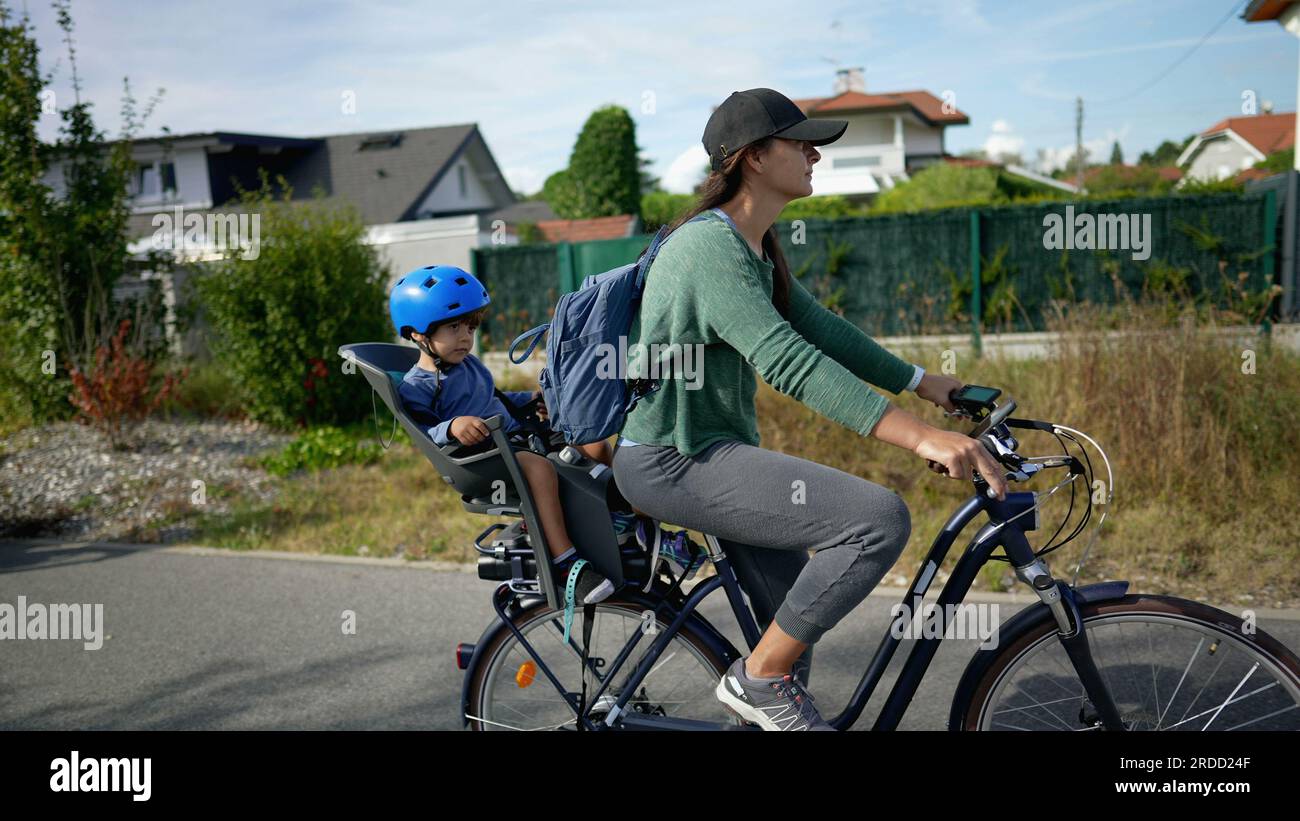 Cyclist mother rides bike outside in green road with child Stock Photo ...
