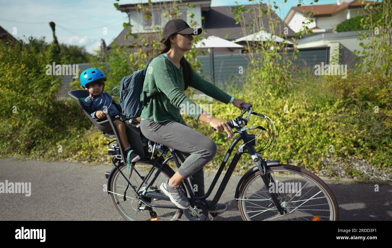 Woman riding bicycle with toddler in back seat mother cyclist Stock ...