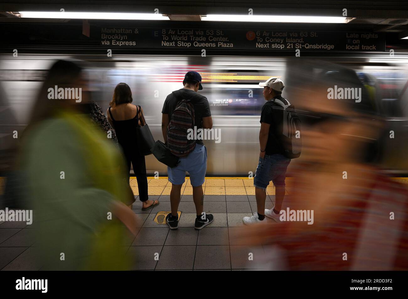 New York, USA. 20th July, 2023. A train passes commuters waiting on a ...