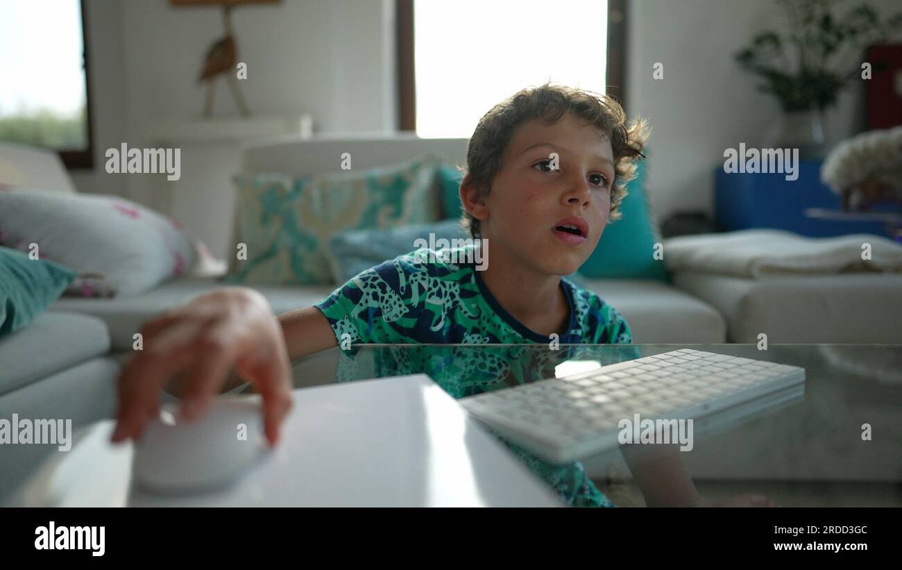 Tired little boy yawning browsing internet online using mouse and ...