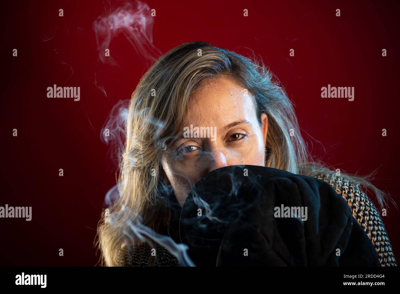 Attractive, confident woman holding a black beret in front of her face ...