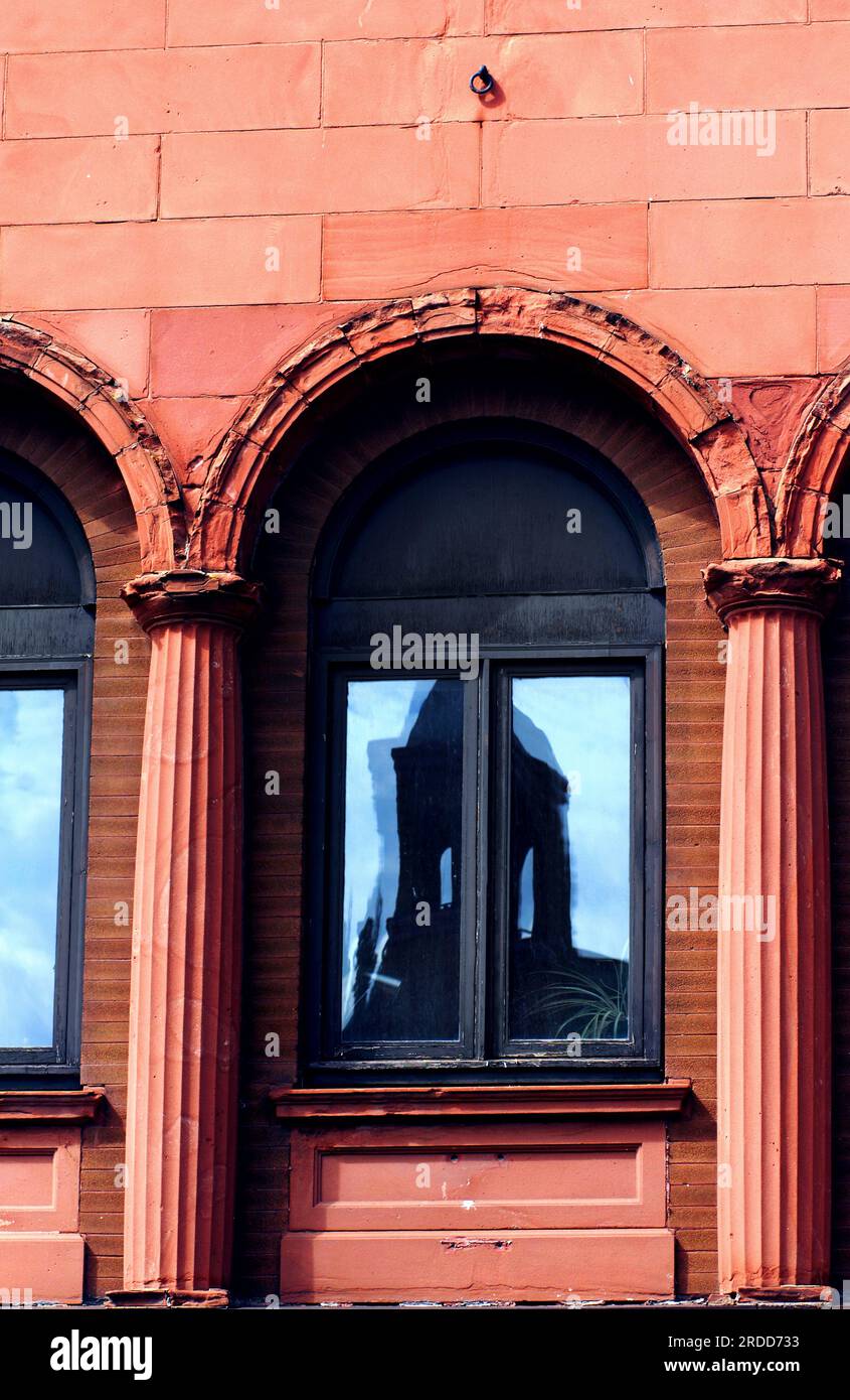 Historic Douglas Hotel reflects in the window of a rundown building in ...