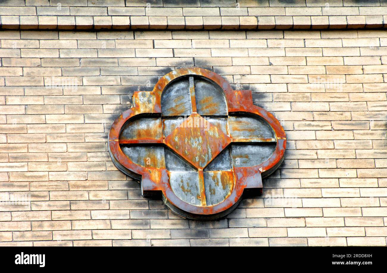 Brick wall has iron architectural design that is weathered and rusting ...